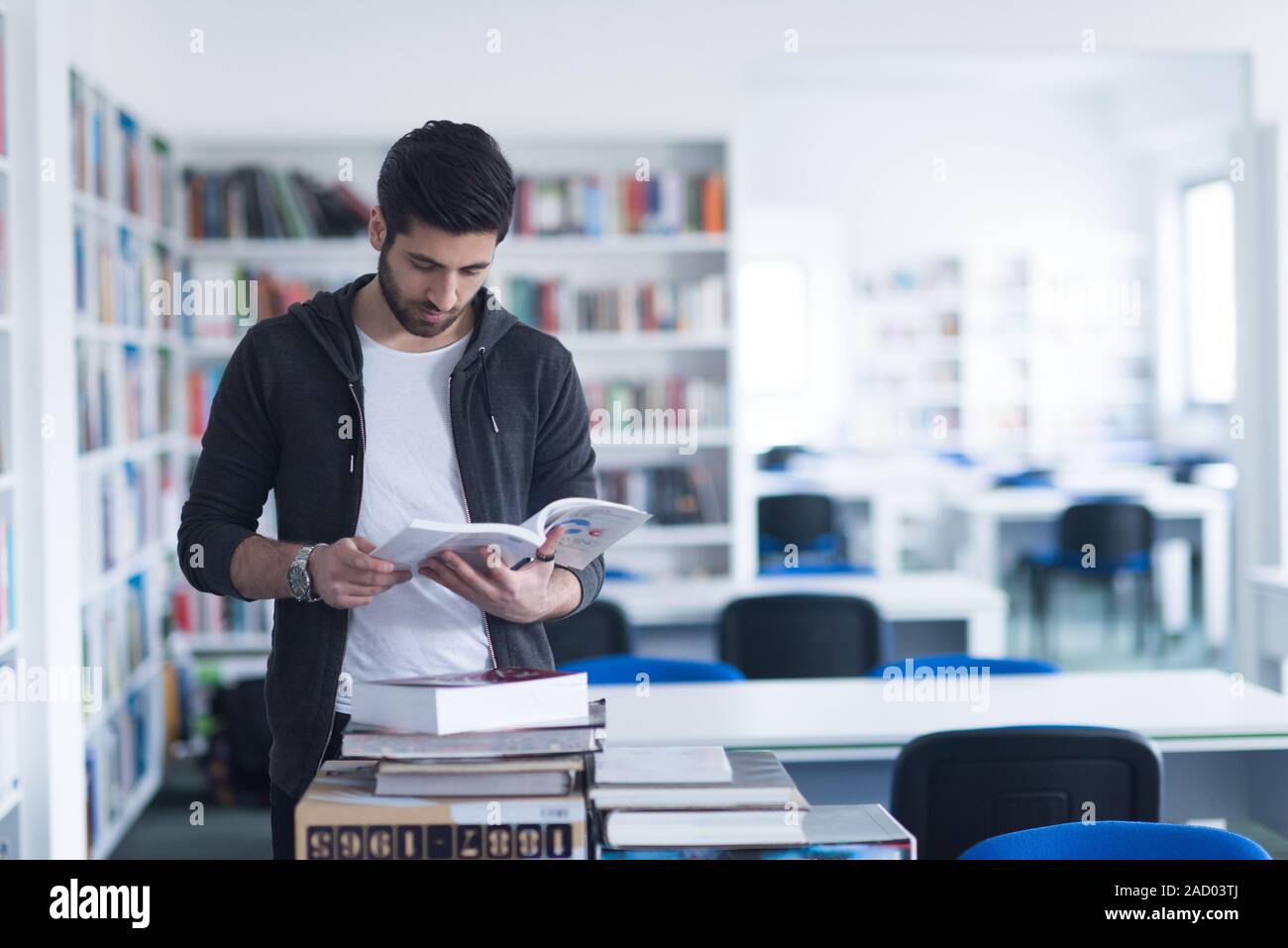 portrait of student while reading book in school library Stock Photo ...