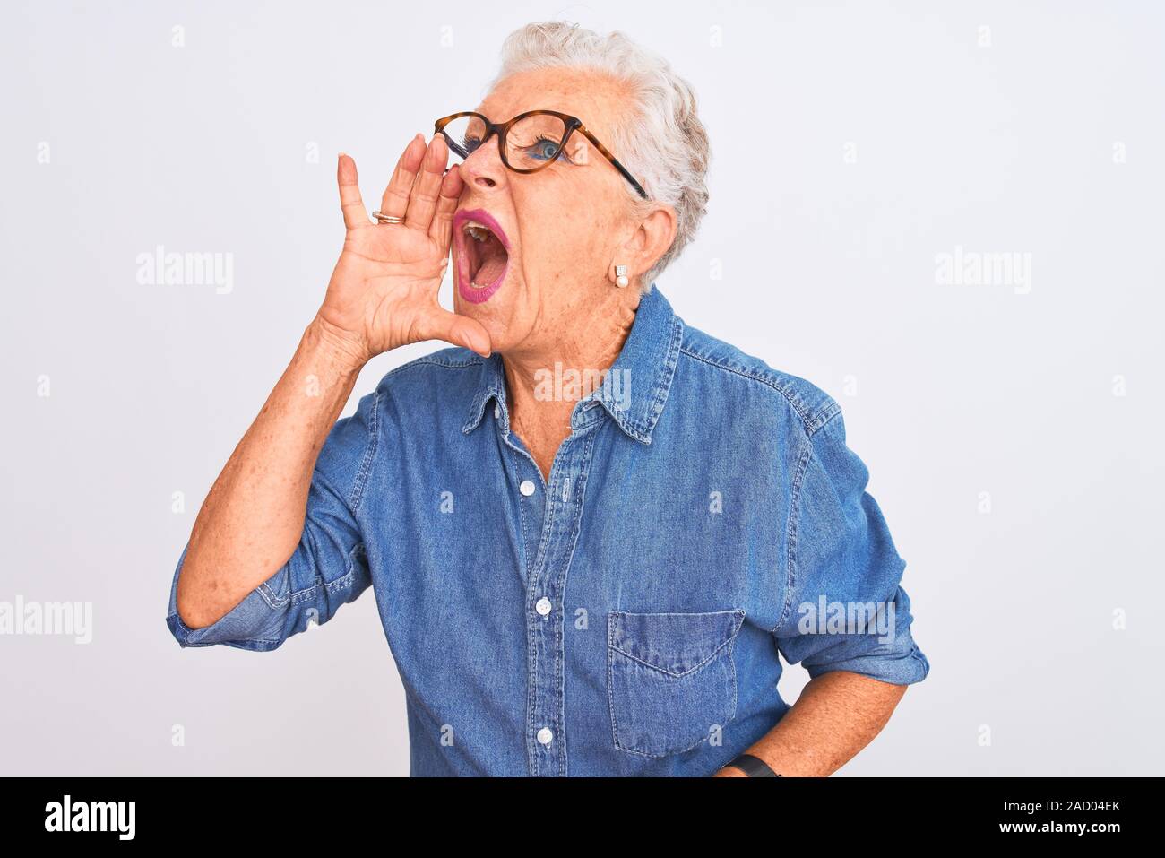 Senior grey-haired woman wearing denim shirt and glasses over isolated ...