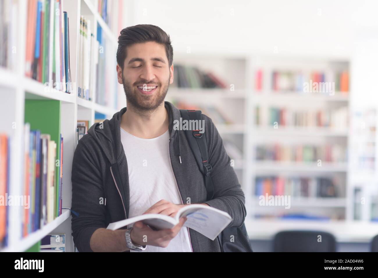 portrait of student while reading book in school library Stock Photo ...