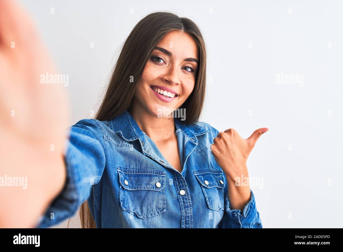Beautiful woman wearing denim shirt make selfie by camera over isolated ...