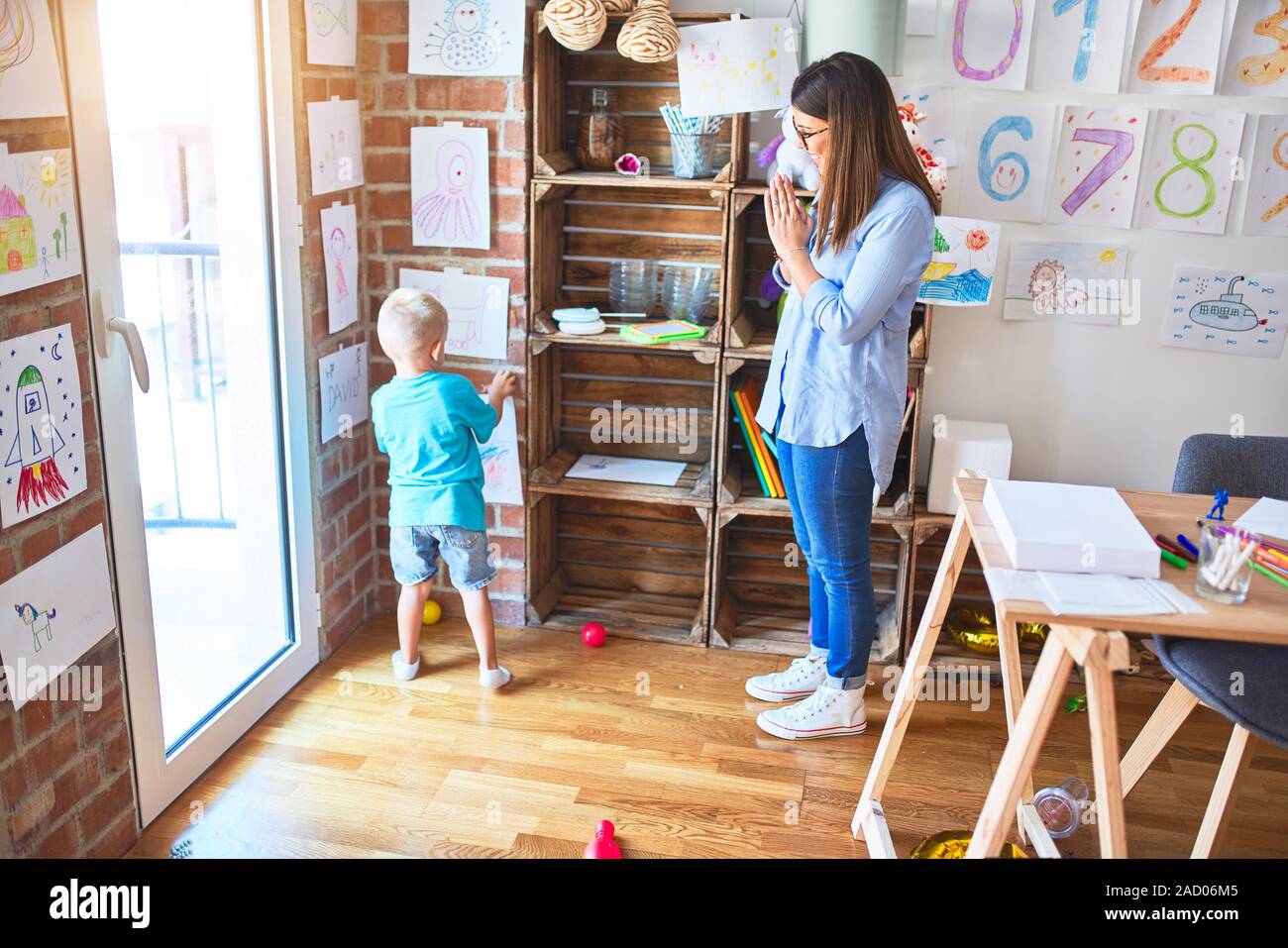Young caucasian child playing at playschool with teacher. Mother and ...