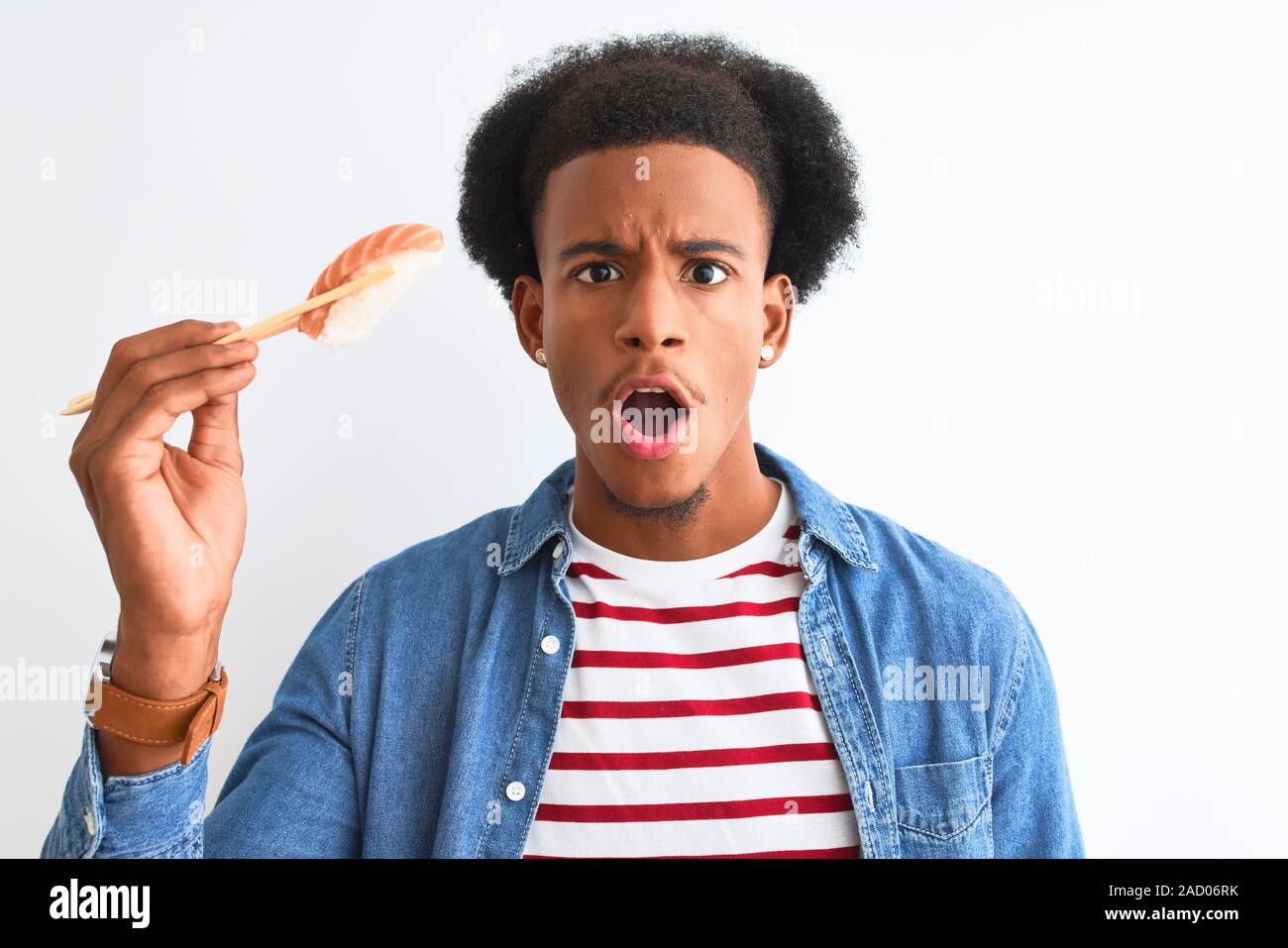 Young african american man eating nigiri using chopsticks over isolated ...