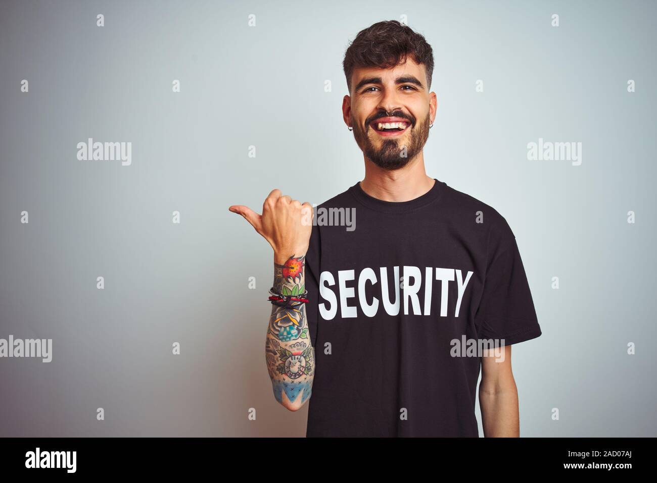 Young safeguard man with tattoo wering security uniform over isolated ...