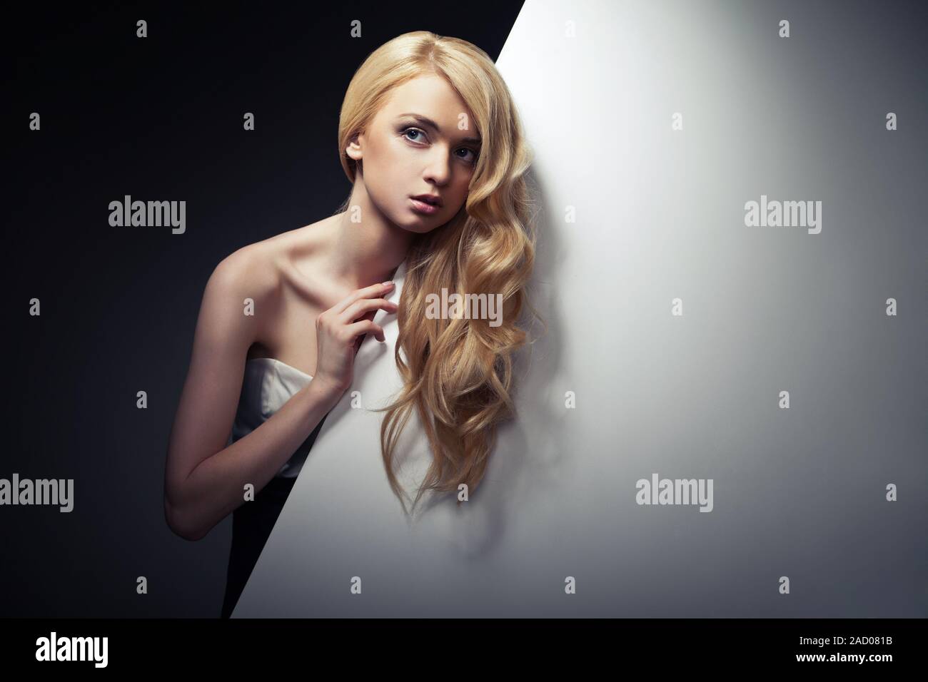pretty blond model hiding behind a big sheet of paper Stock Photo - Alamy