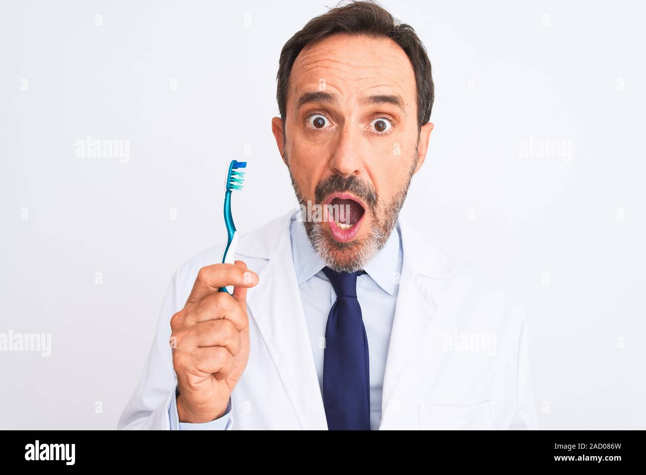Middle age dentist man holding toothbrush standing over isolated white ...