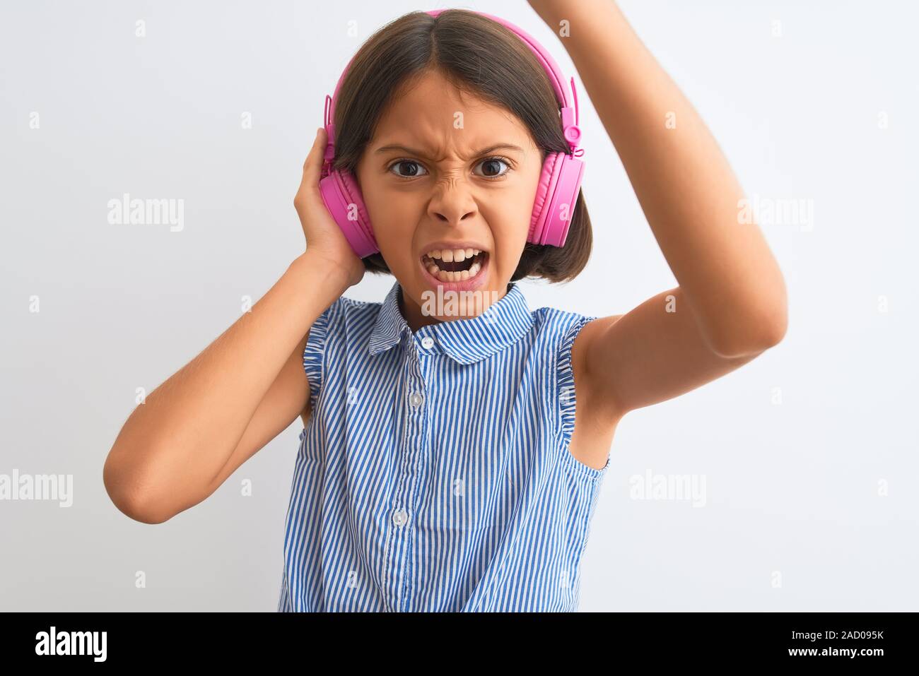 Beautiful child girl listening to music using headphones over isolated ...
