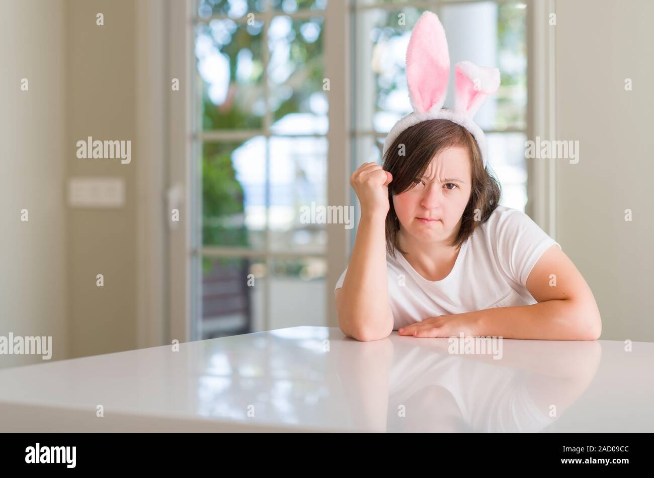Down syndrome woman at home wearing easter rabbit ears annoyed and ...
