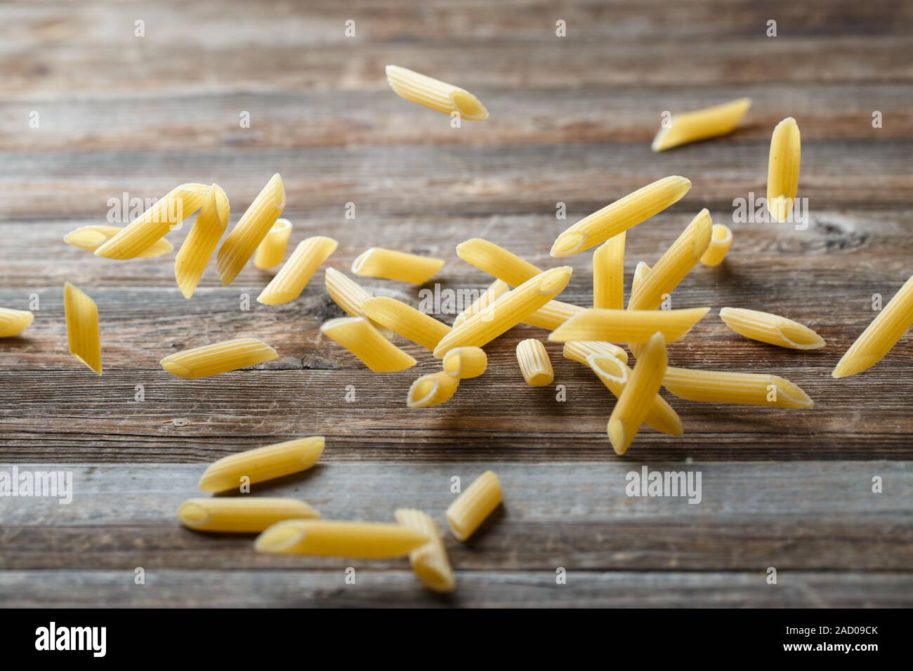 Falling penne pasta. Flying yellow raw macaroni over black background ...