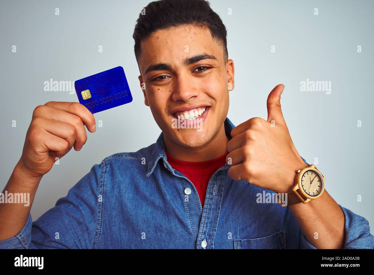Young brazilian customer man holding credit card standing over isolated ...