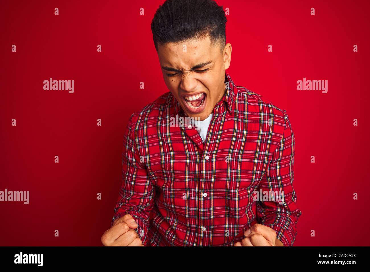 Young brazilian man wearing shirt standing over isolated red background ...