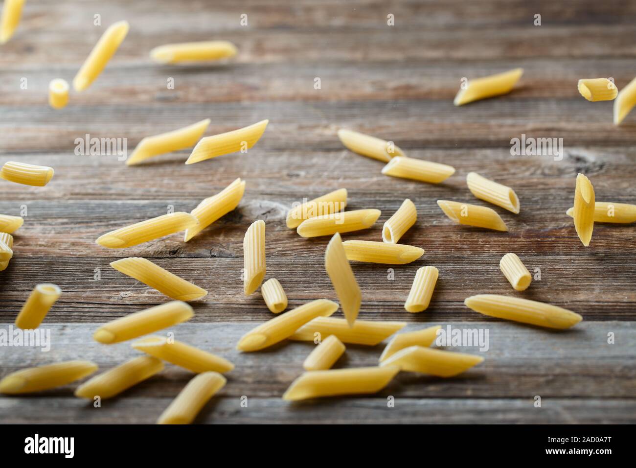 Falling penne pasta. Flying yellow raw macaroni over black background ...