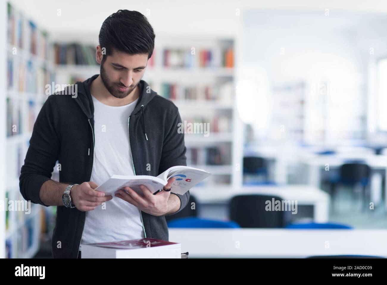 portrait of student while reading book in school library Stock Photo ...