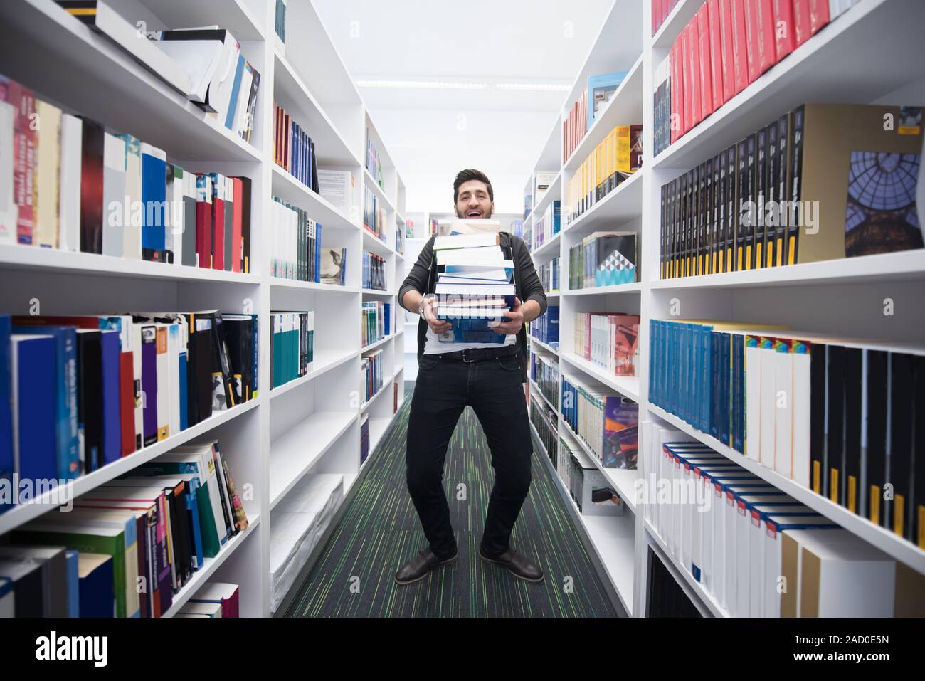 Student holding lot of books in school library Stock Photo - Alamy