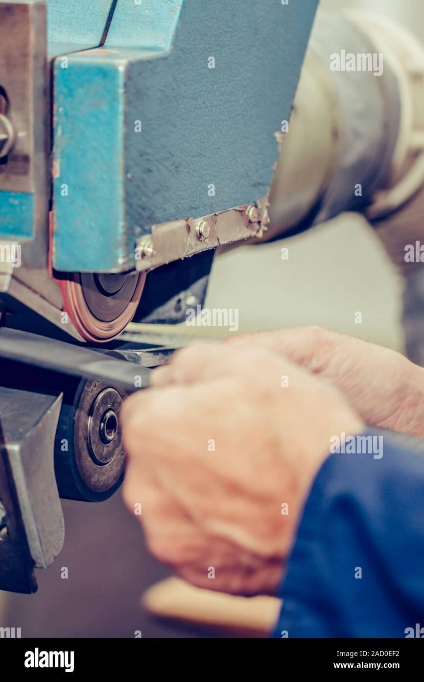 Hands of an experienced shoemaker using special machine tool for making ...