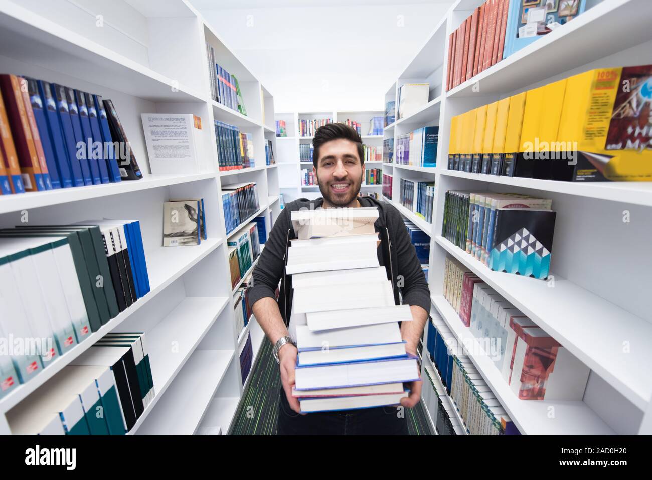 Student holding lot of books in school library Stock Photo - Alamy