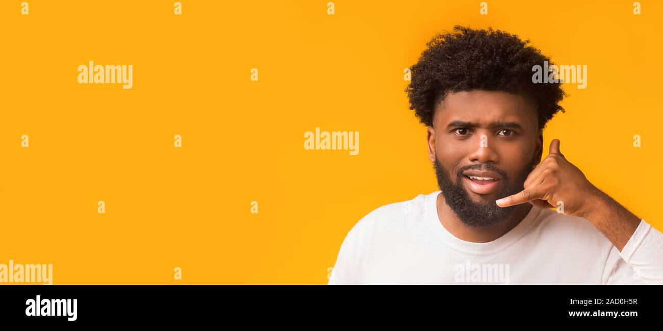 Persistent afro guy showing call me gesture over orange background ...