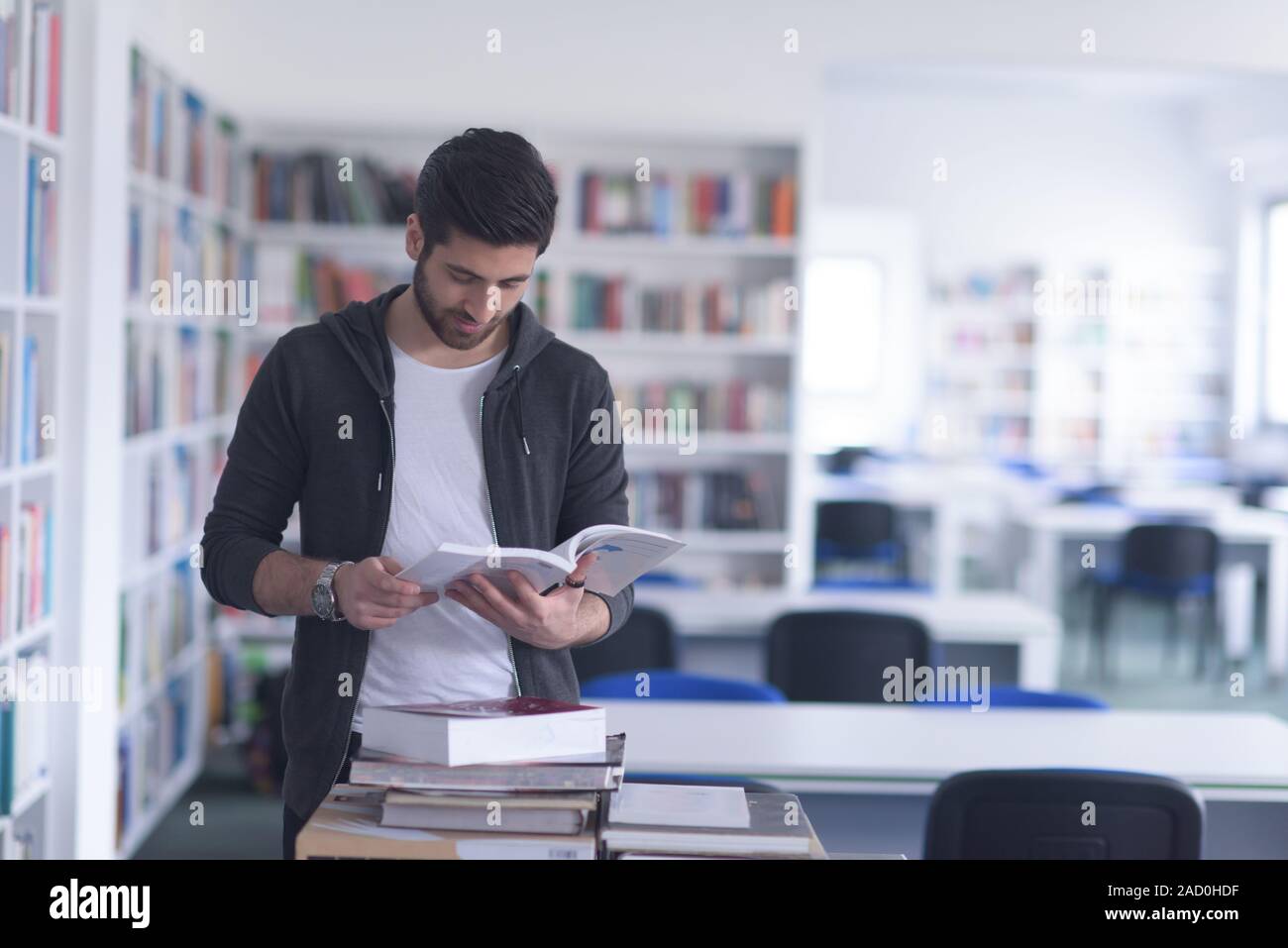 portrait of student while reading book in school library Stock Photo ...