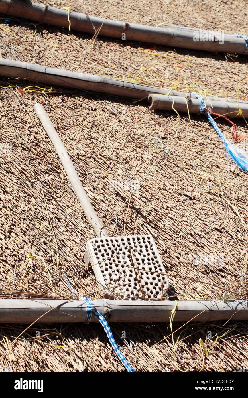 Thatching a roof. Close-up of a traditional thatching tool on the roof ...