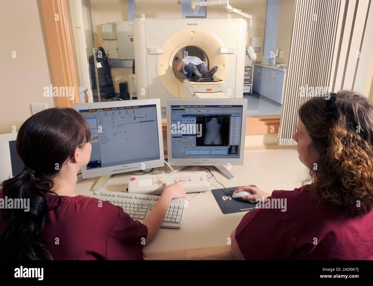 CT scanning for radiotherapy. Medical workers in a scanning room in a ...