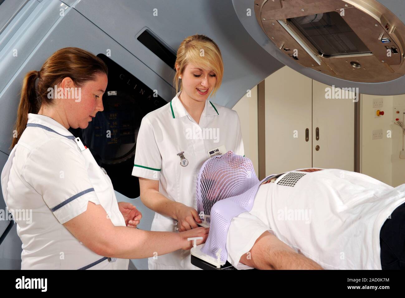 Linear accelerator X-ray radiotherapy. Medical workers and a patient in ...