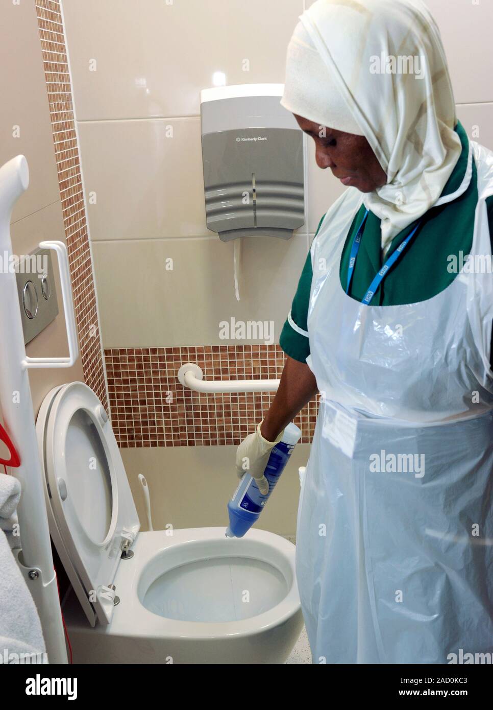 Hospital toilet cleaning. Hospital cleaner putting toilet cleaner fluid ...