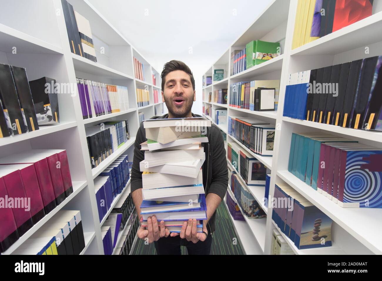 Student holding lot of books in school library Stock Photo - Alamy