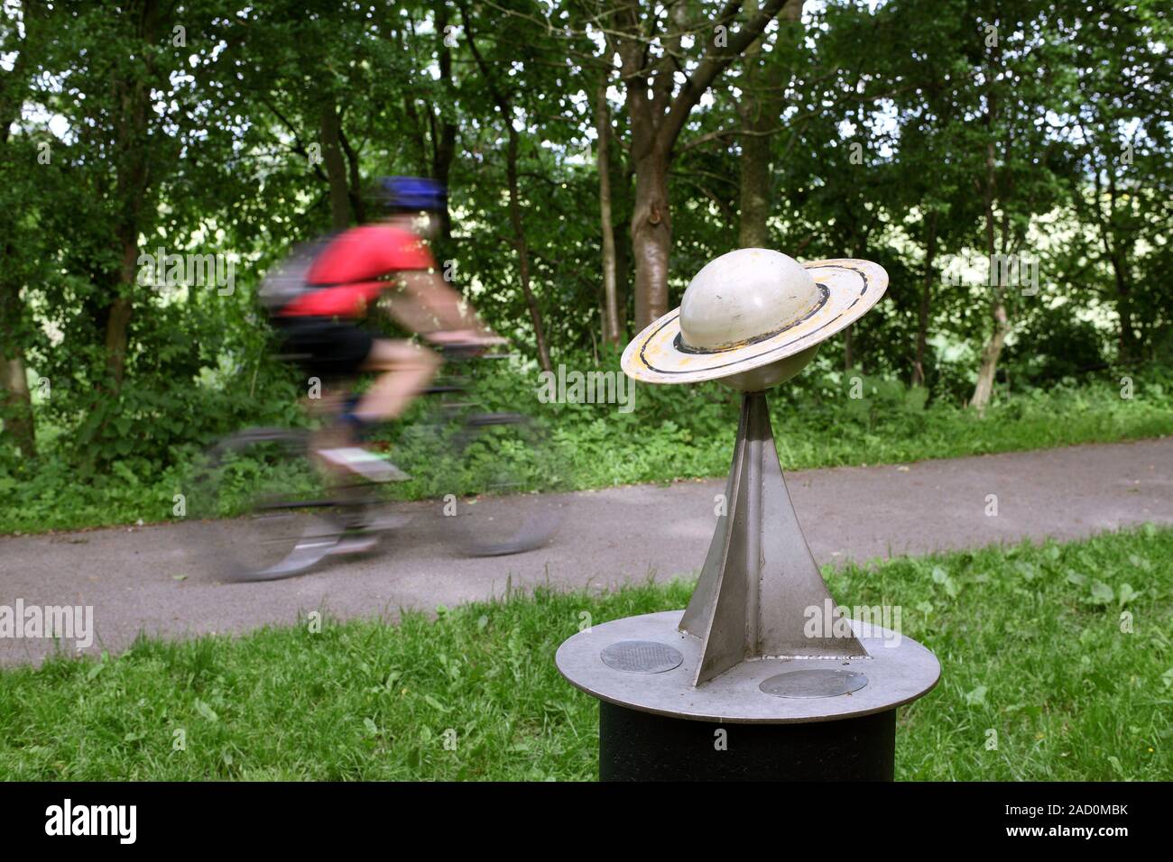 Solar system themed cycle route. Cyclist passing a model of the planet ...