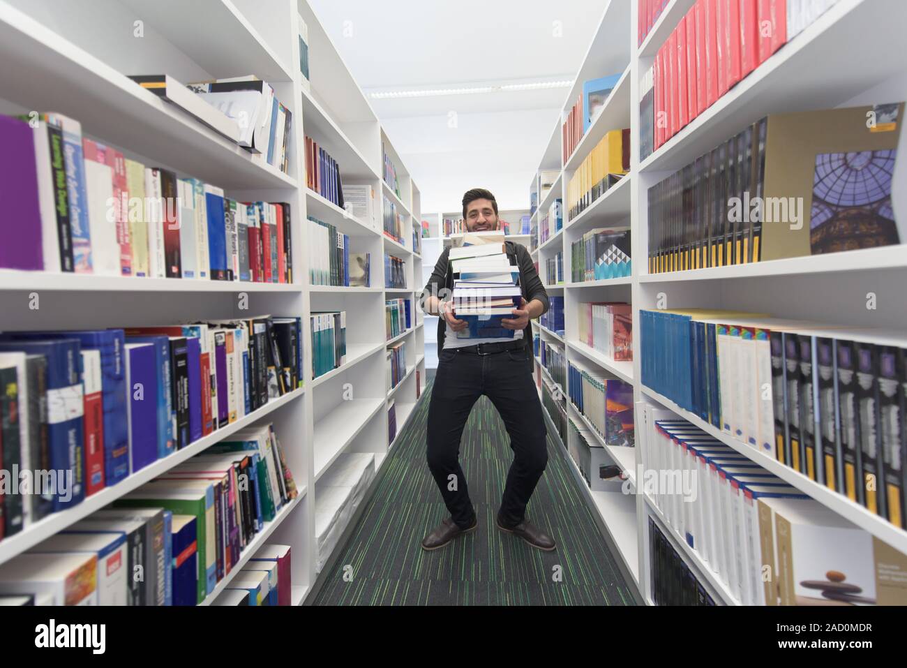 Student holding lot of books in school library Stock Photo - Alamy