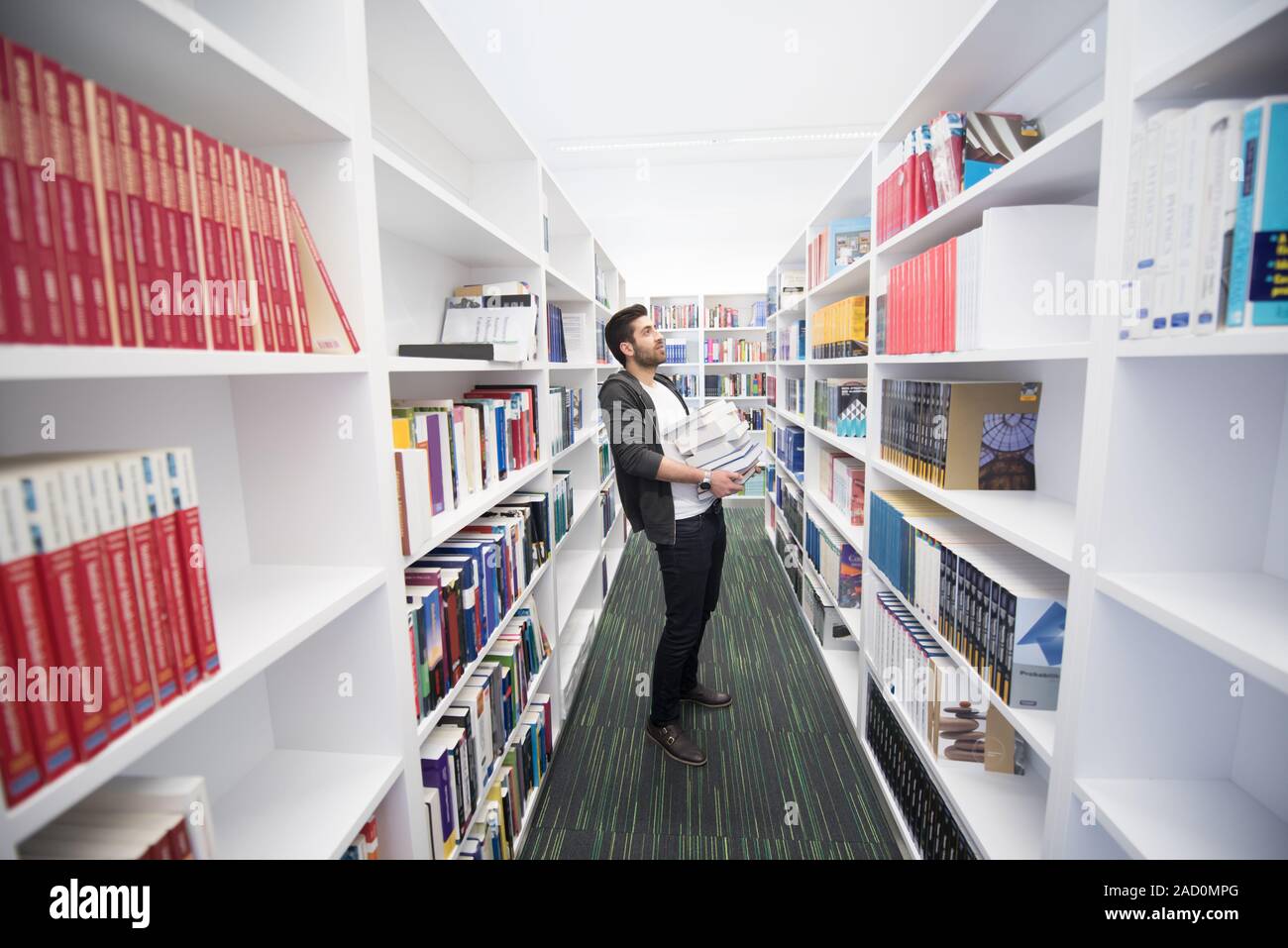 Student holding lot of books in school library Stock Photo - Alamy
