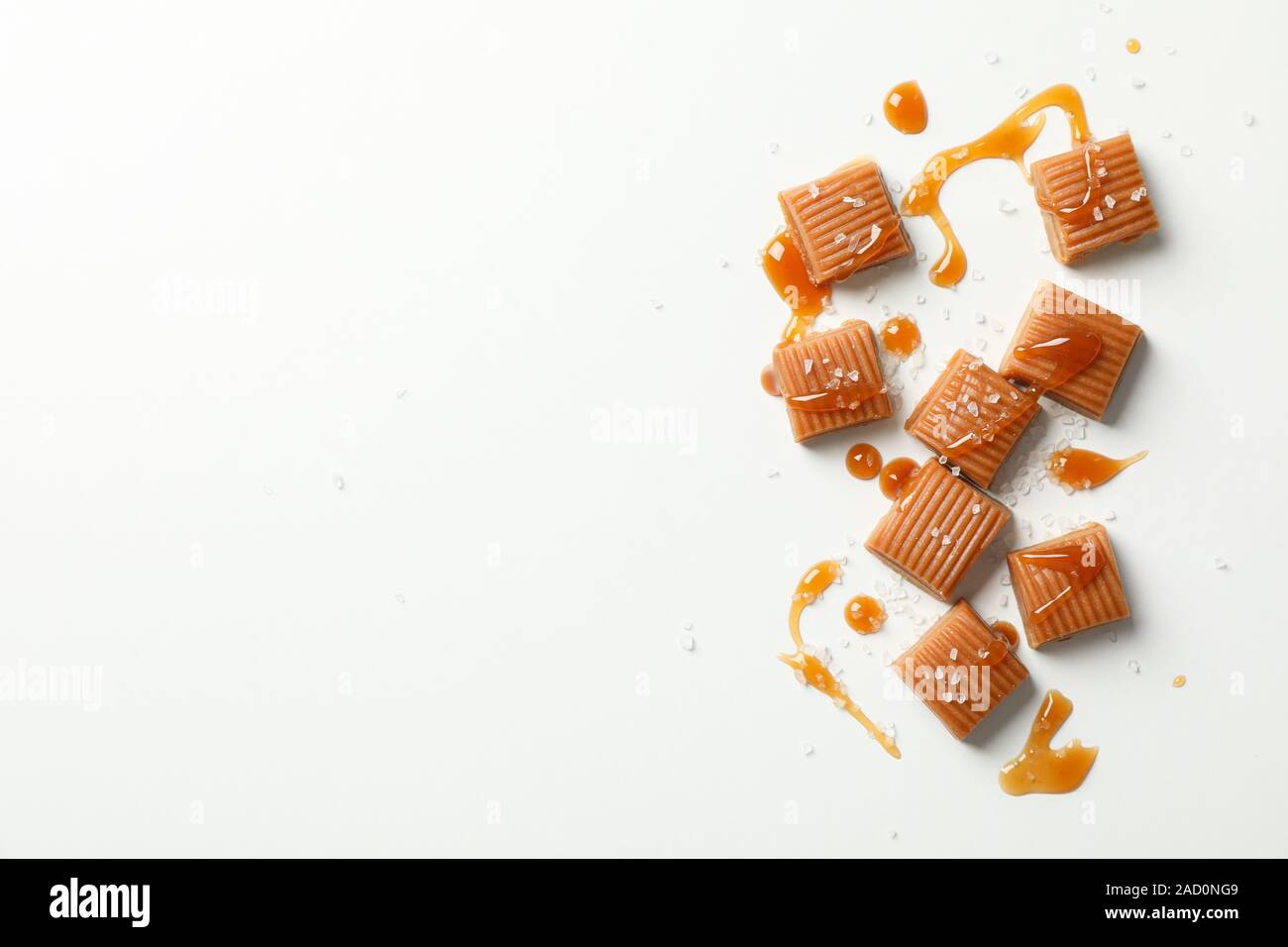 Salted caramel candies and sauce on white background, space for text ...