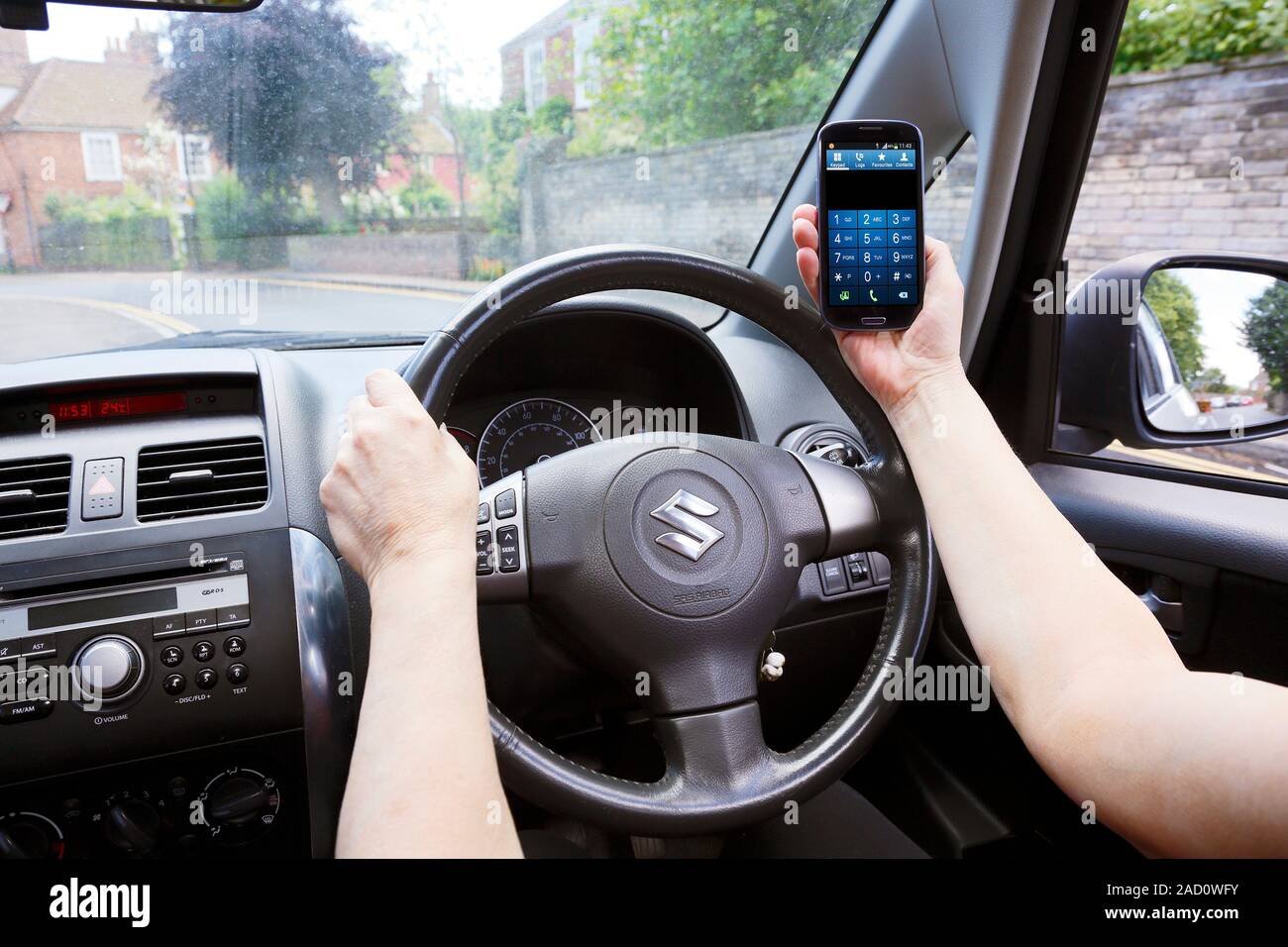 Phone use while driving. Driver's view of a driver with one hand on the ...