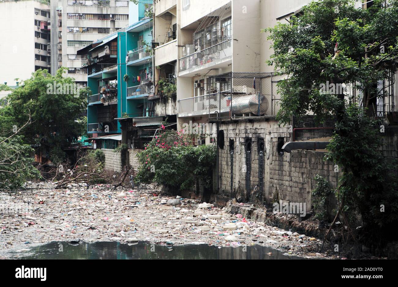 Polluted river. View of houses overlooking a heavily polluted river in ...