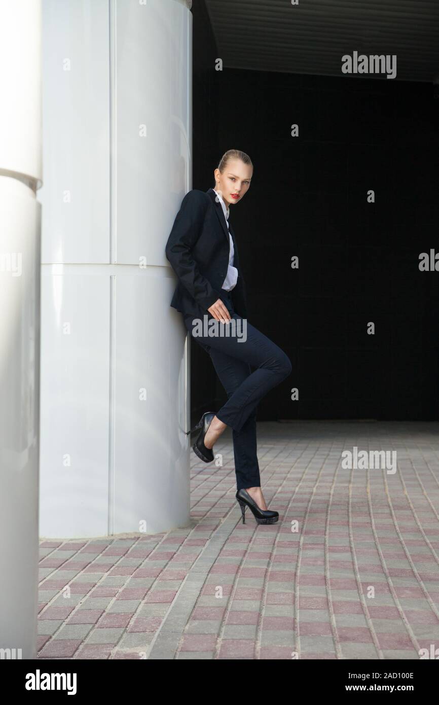 Attractive woman in suit posing near white column Stock Photo - Alamy