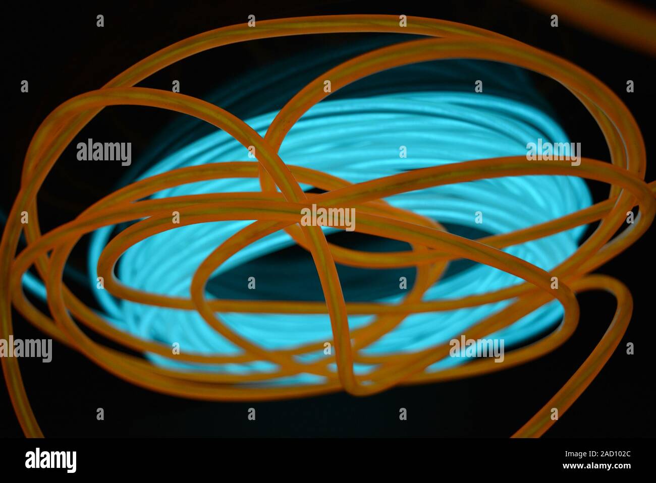 A bright coil of turquoise, sky blue luminous wire with chaotic wires ...