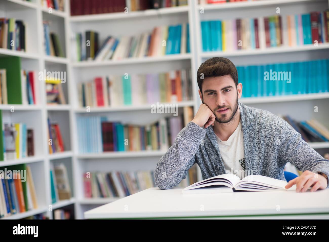 portrait of student while reading book in school library Stock Photo ...