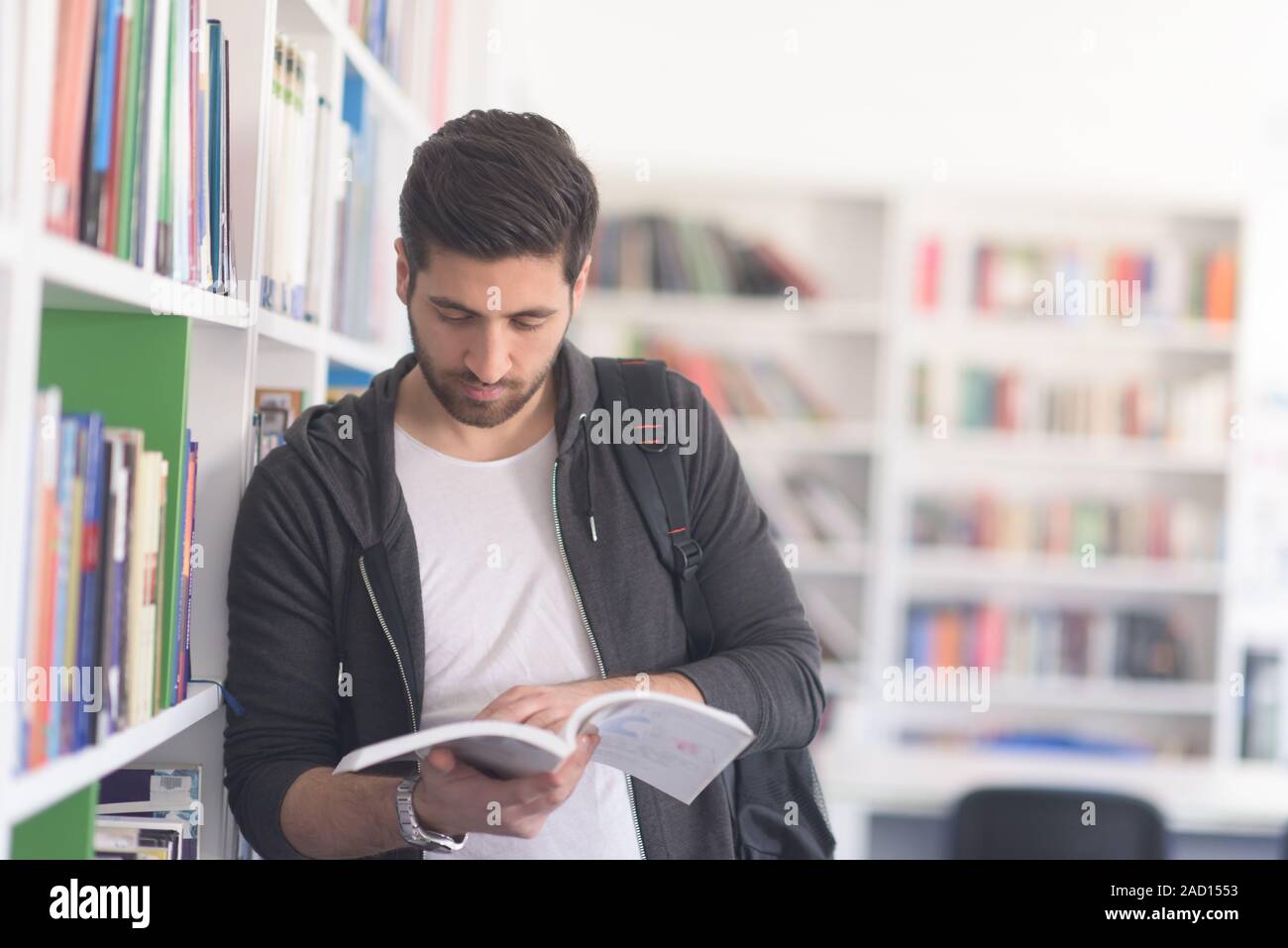 portrait of student while reading book in school library Stock Photo ...