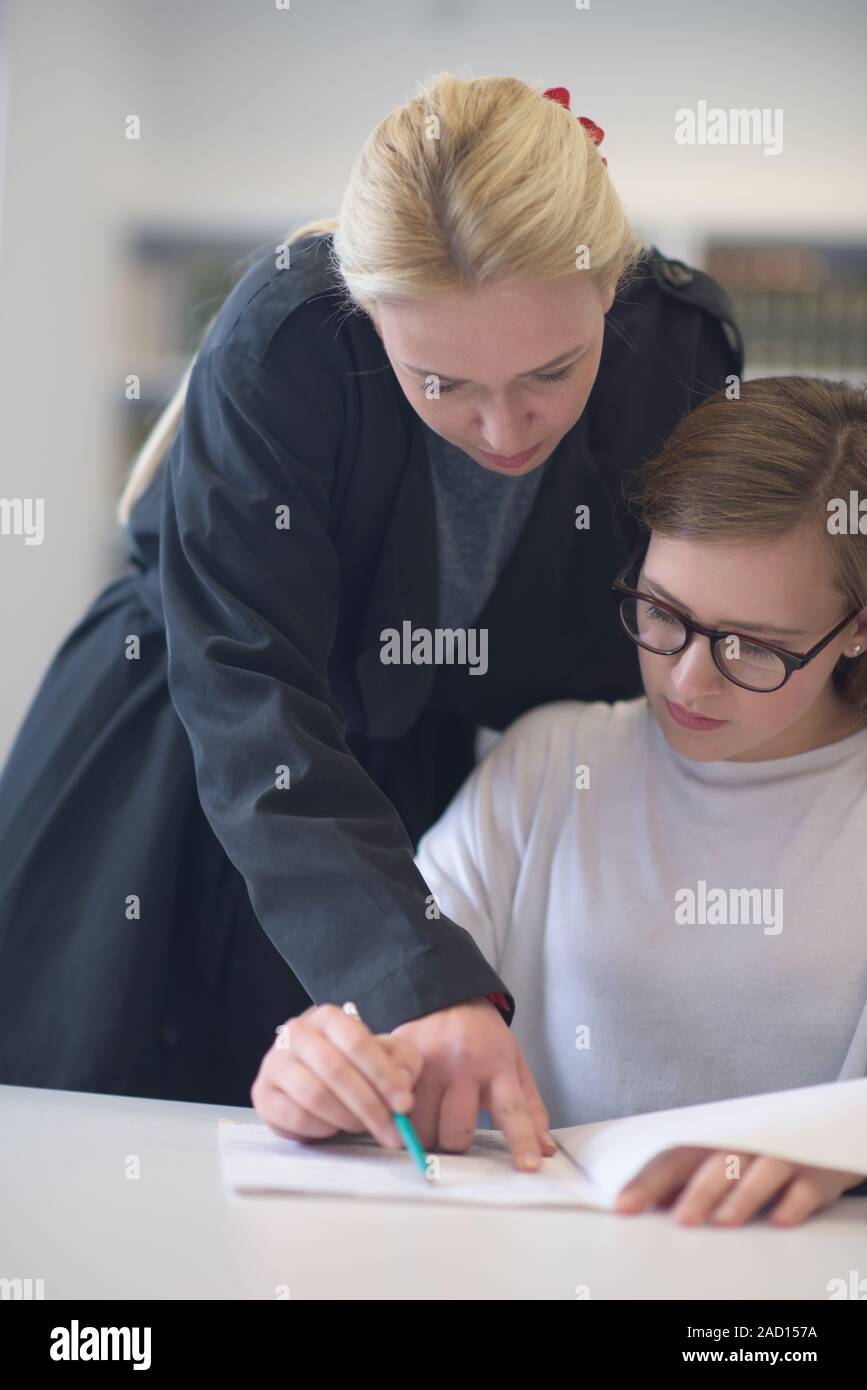 female teacher helping students on class Stock Photo - Alamy