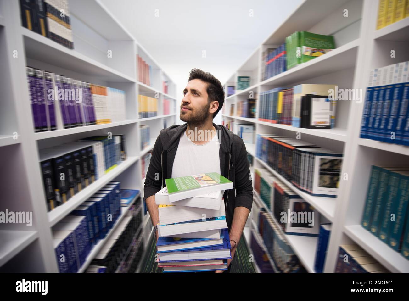 Student holding lot of books in school library Stock Photo - Alamy