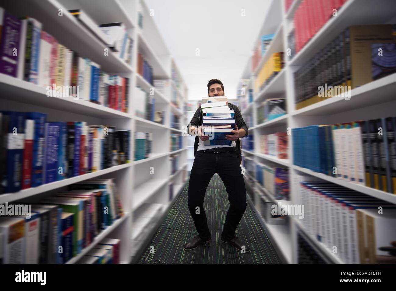 Student holding lot of books in school library Stock Photo - Alamy