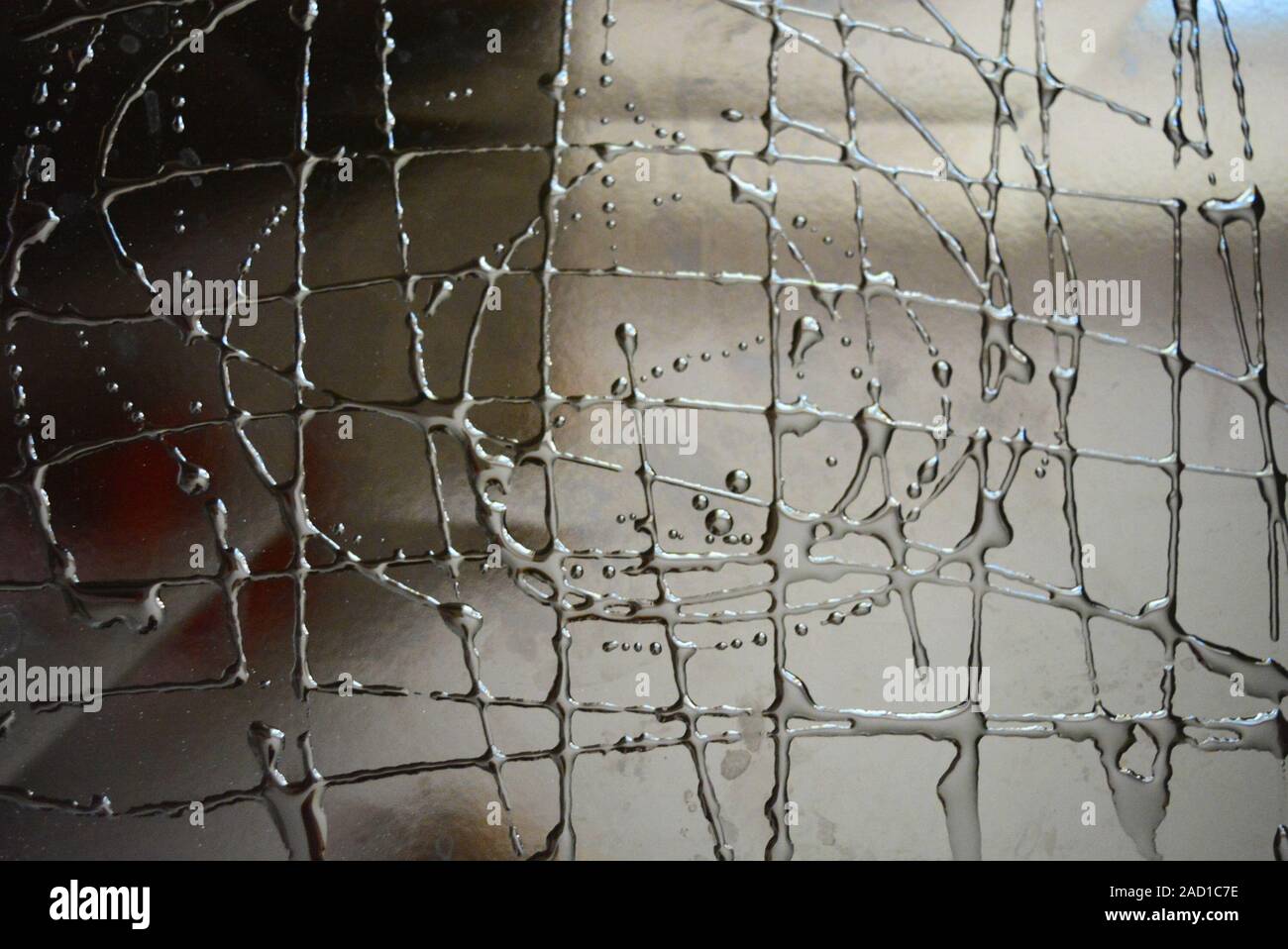 Water and oil droplets in the form of art inscriptions on a black metal ...