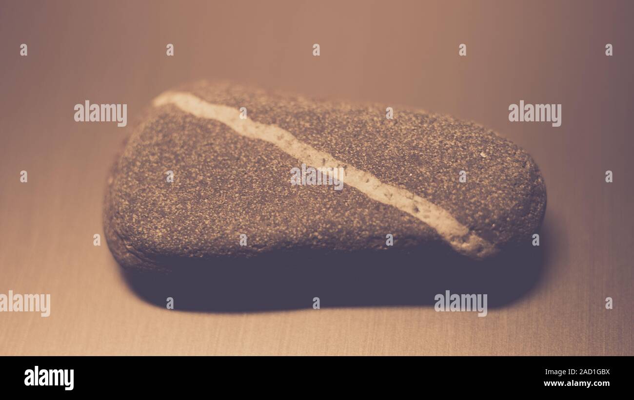 Pebble stone with natural diagonal white line on the table Stock Photo ...