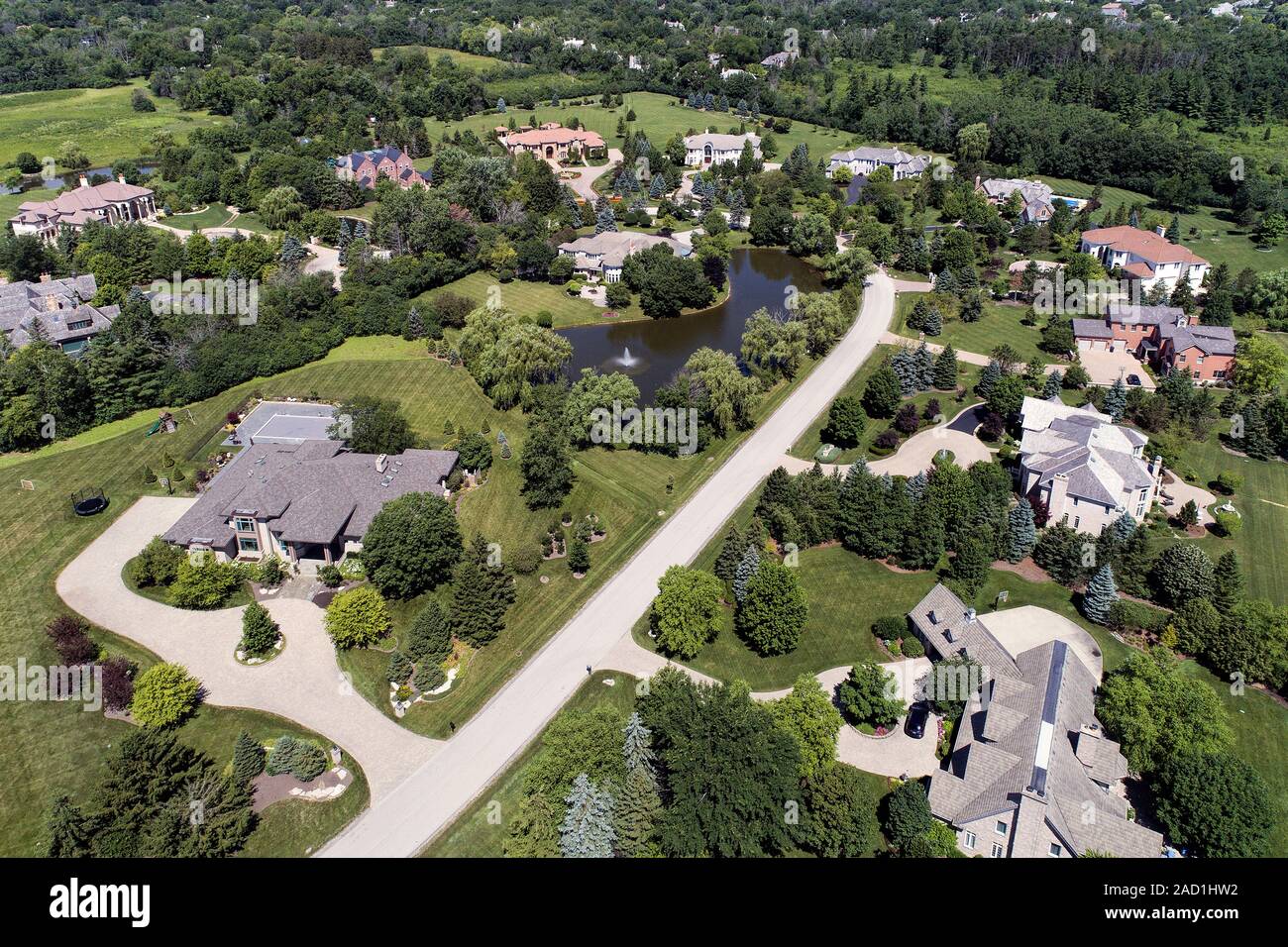 Aerial view of a luxury neighborhood with mature trees and a pond in a ...