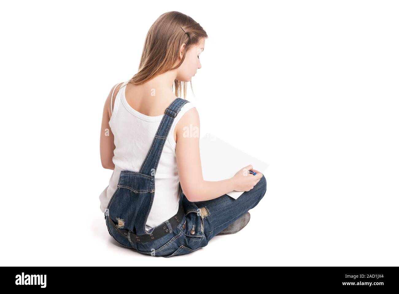 Young woman happily sitting on the floor drawing in her note pad. Back ...