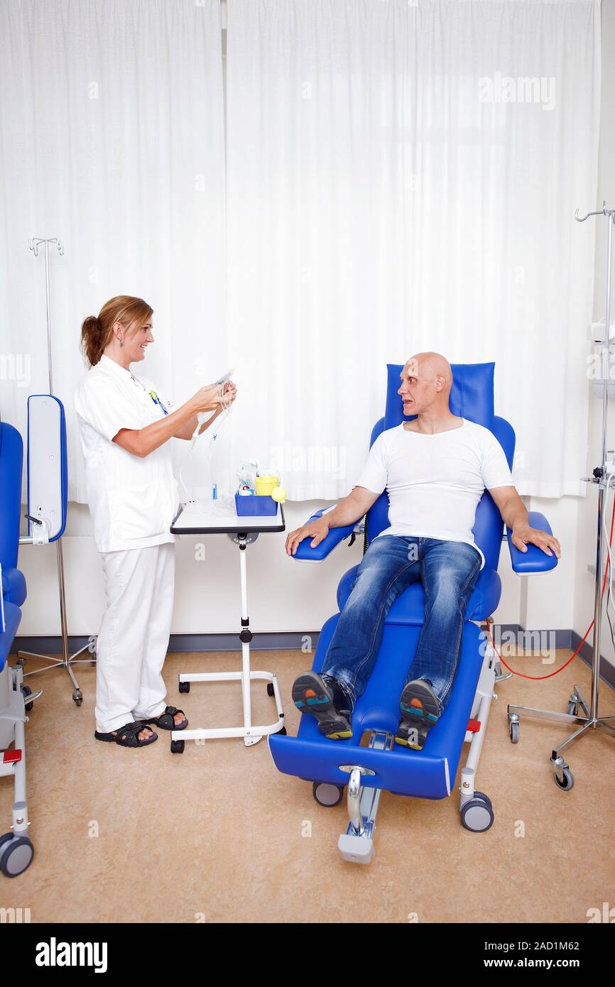 Chemotherapy treatment. Nurse preparing the IV (intravenous) drip for a ...