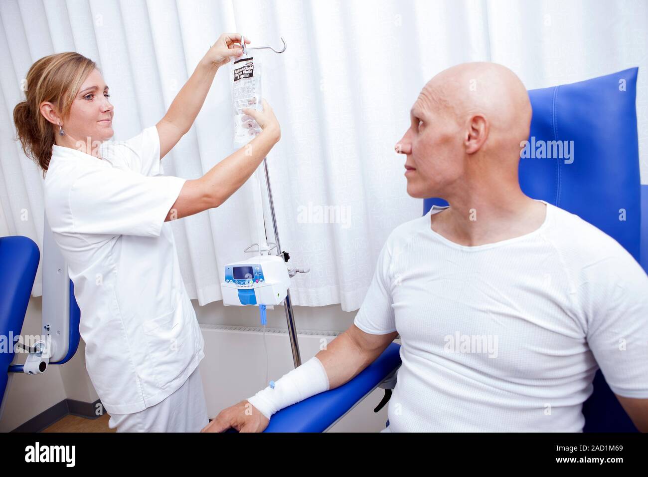 Chemotherapy treatment. Nurse preparing the IV (intravenous) drip for a ...