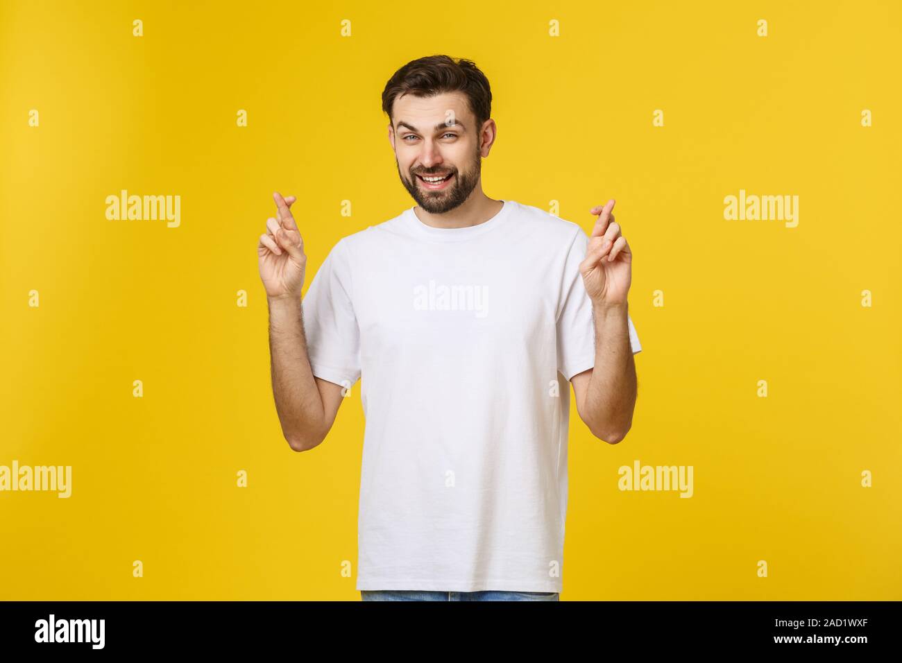 Young man making a wish isolated on yellow background Stock Photo - Alamy