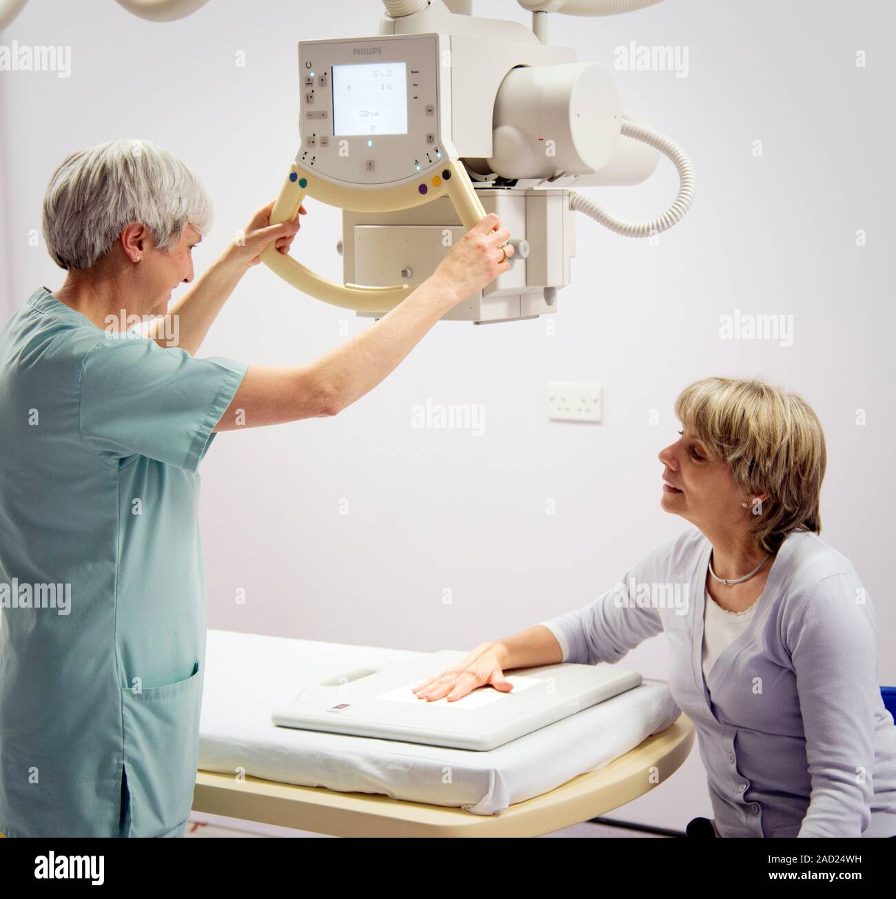 Radiographer preparing a hand X-ray. Hospital radiographer positioning ...