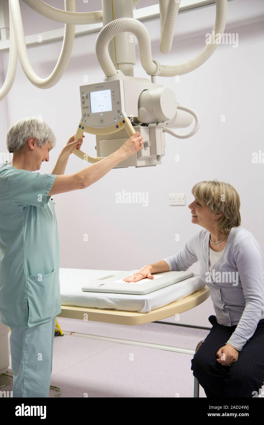 Radiographer preparing a hand X-ray. Hospital radiographer positioning ...
