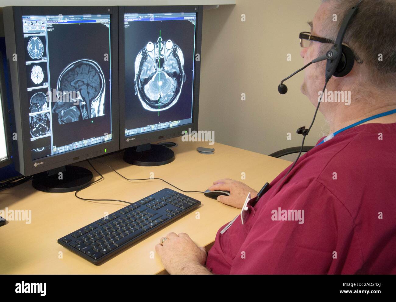 Radiographer processing an MRI scan. Radiographer, using a headset to ...