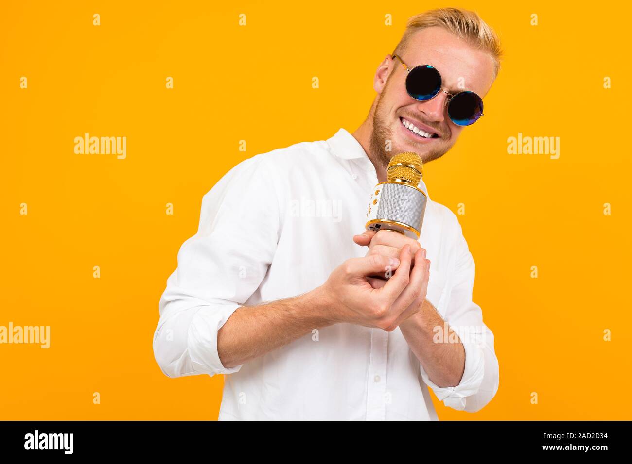portrait of a smiling european man in a white shirt singing into a ...